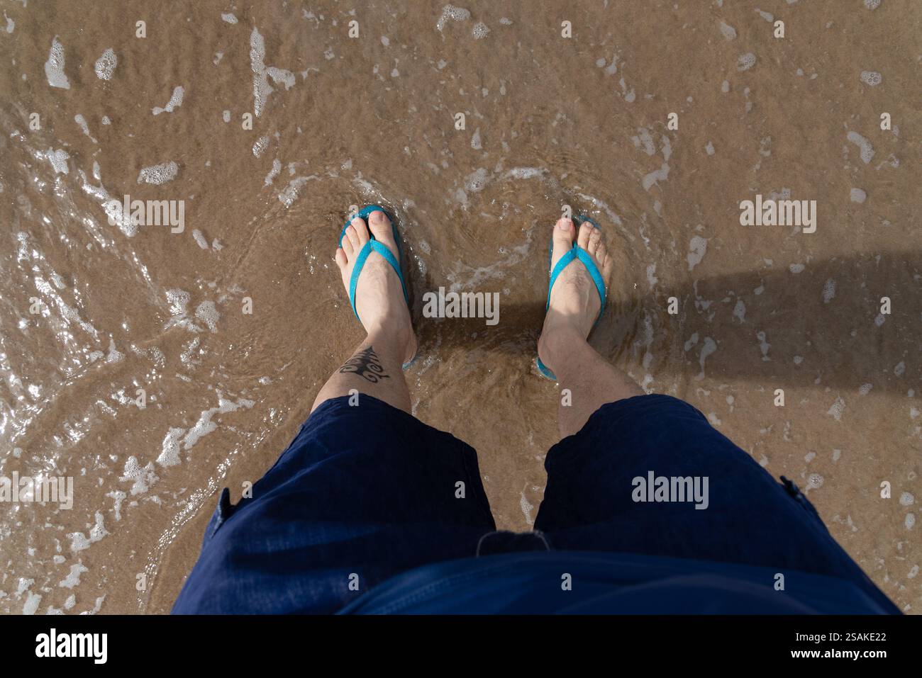 Top view of shod feet in the water at the beach. relaxation concept ...