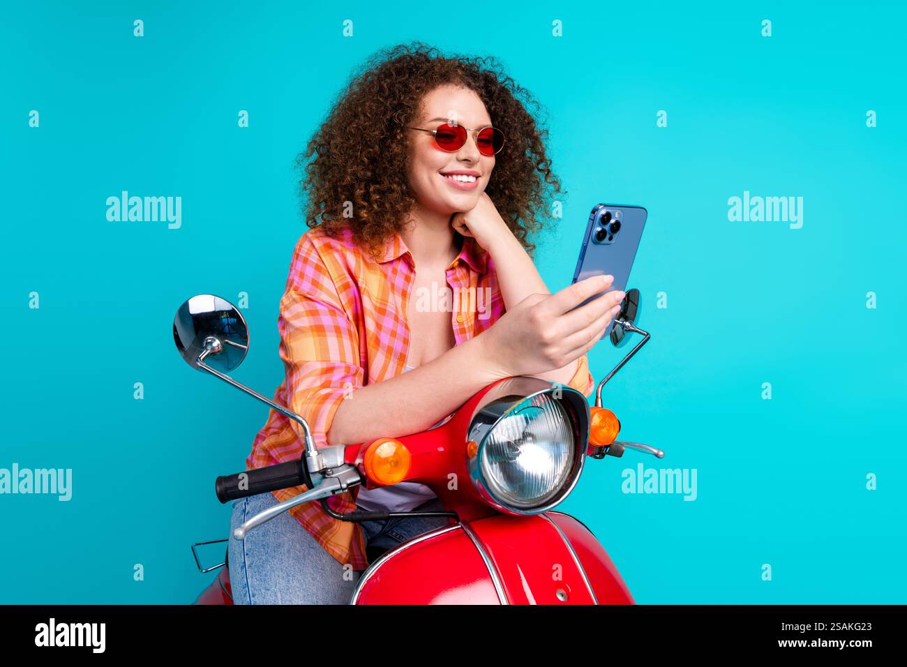 Smiling young woman taking a selfie on a scooter with a turquoise ...