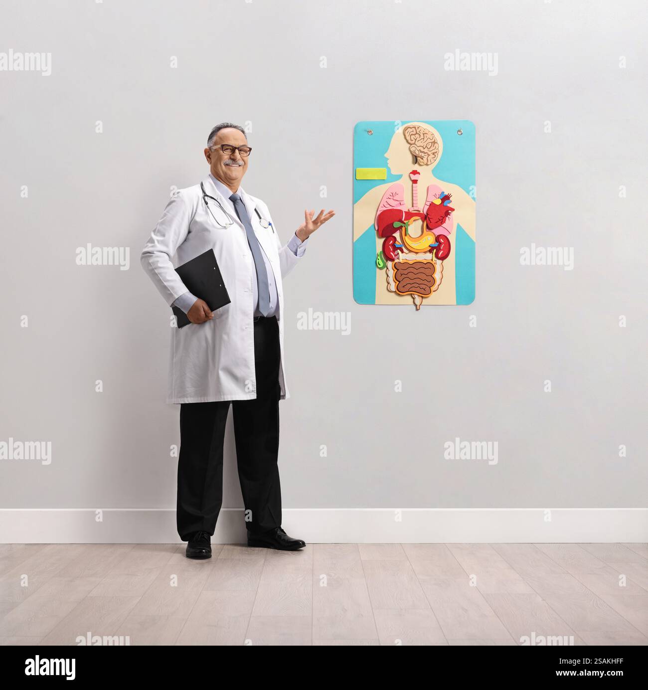 Male doctor in a clinic standing next to a poster of a human body and ...