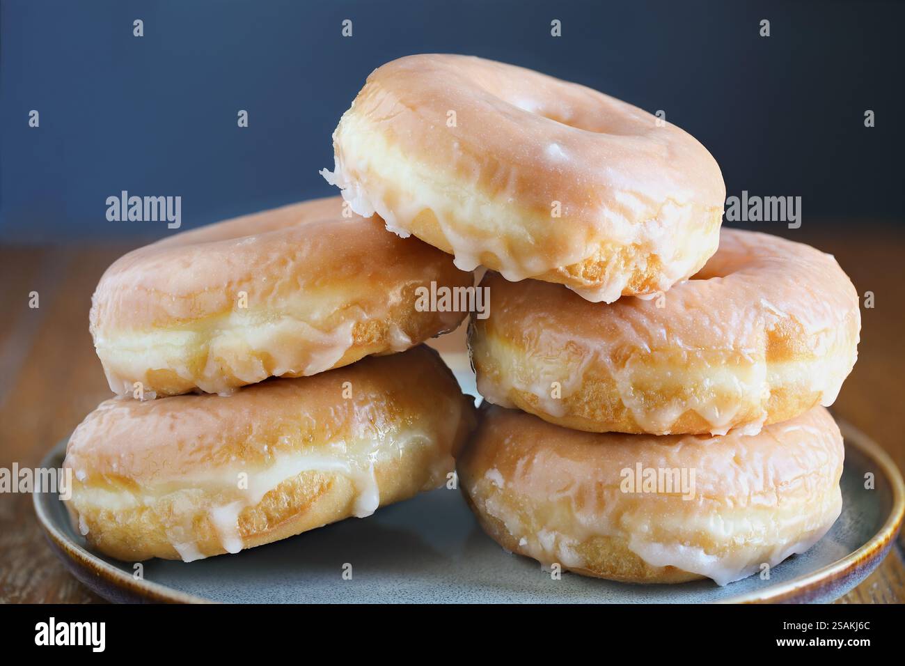 Tall stacked of glazed donuts over a rustic background. Selective focus ...