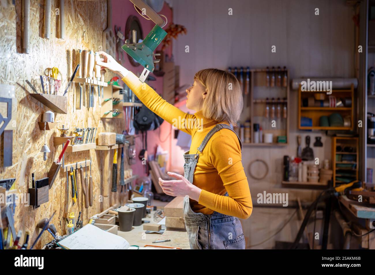 Organized efficient workspace in wooden workshop. Woman joiner organize ...