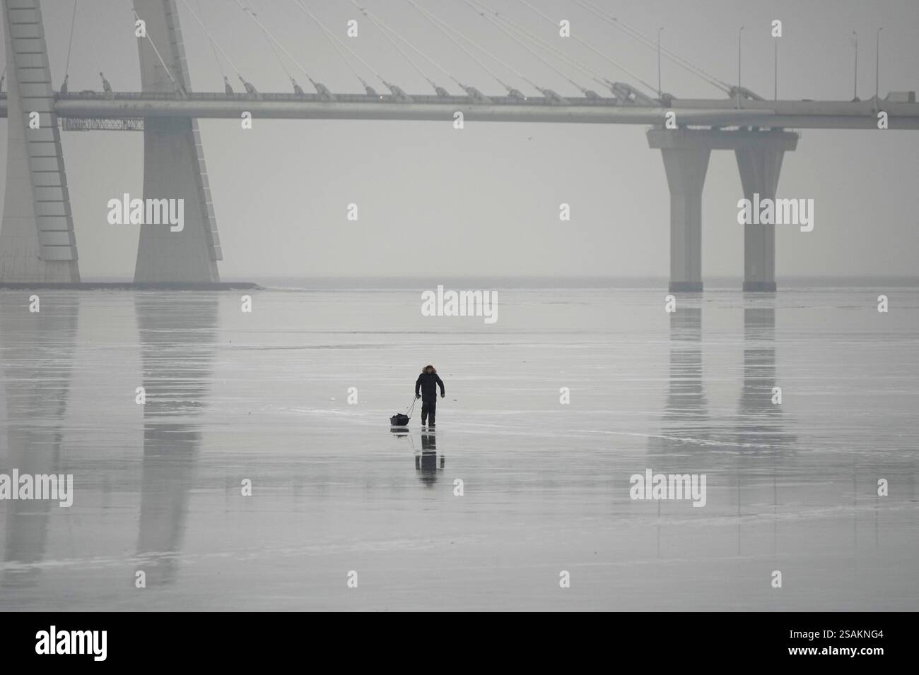 A fisherman walks on melting ice not far from shore on the Gulf of ...