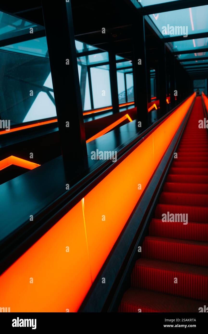 A futuristic escalator illuminated by vibrant red and orange lights ...