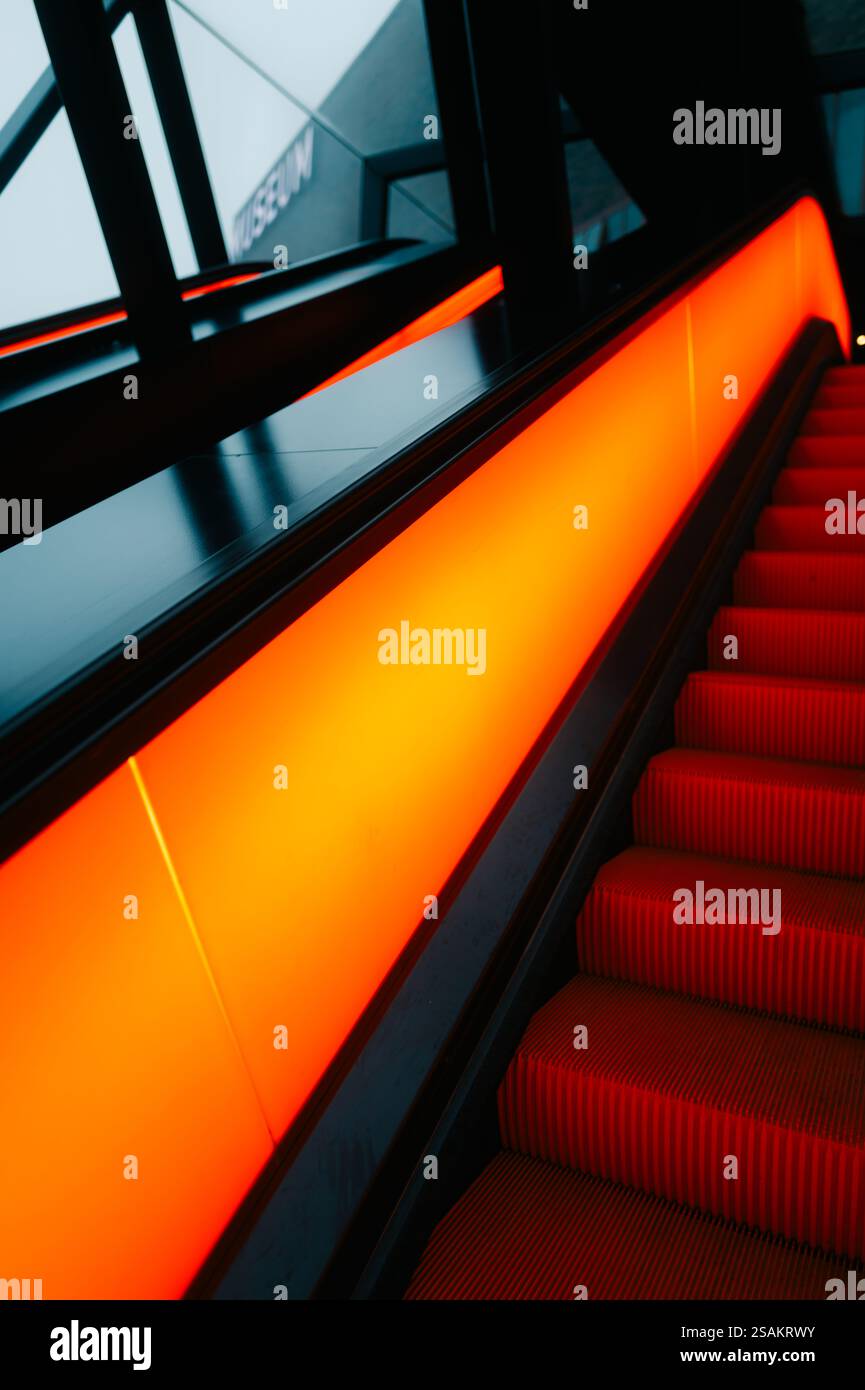 A futuristic red escalator at Zollverein, illuminated by vibrant orange ...