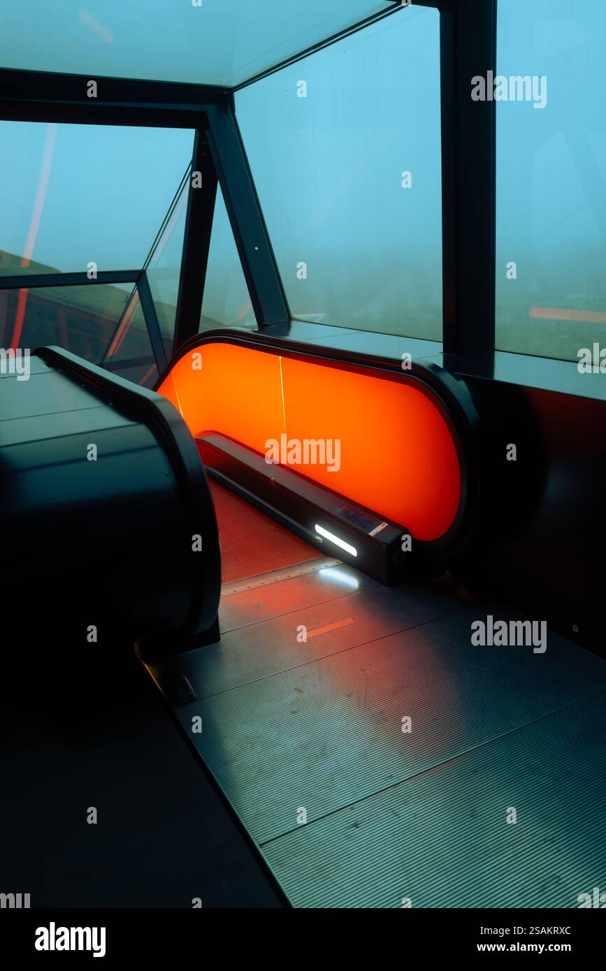 A futuristic escalator with bright red lights leading upwards inside a ...