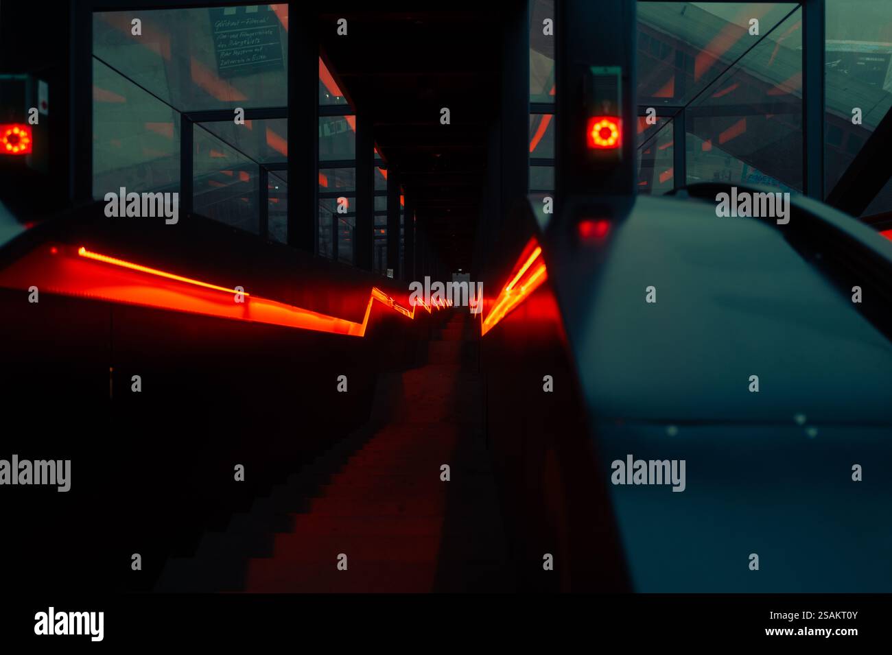 A futuristic escalator with bright red lights leading upwards inside a ...