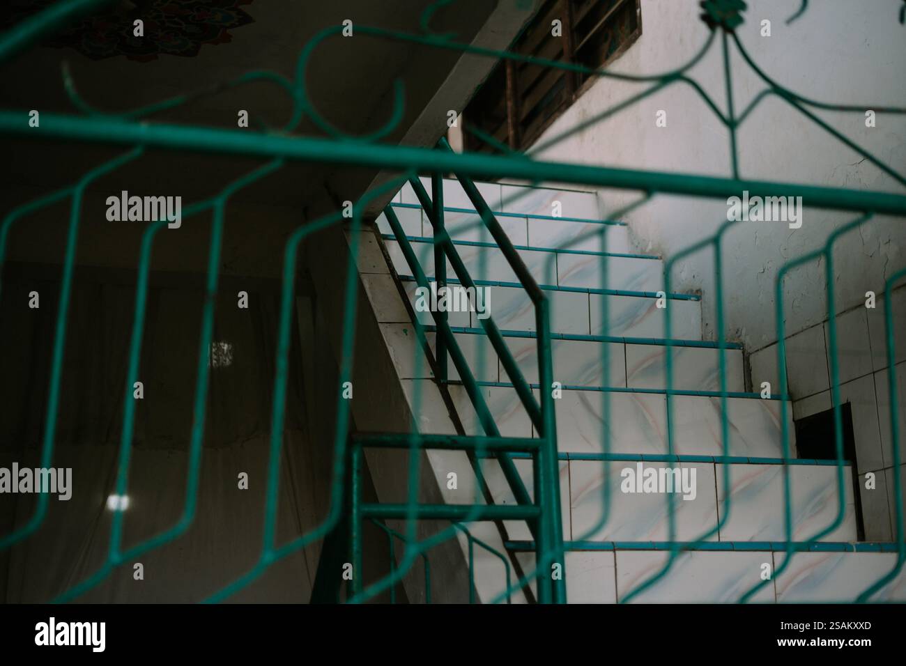 View of a staircase through a green railing, adding a sense of depth ...