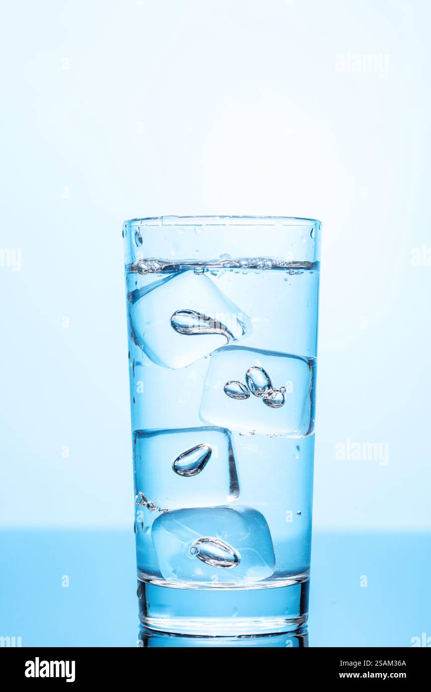 A clear glass filled with chilled water and ice cubes, creating a ...
