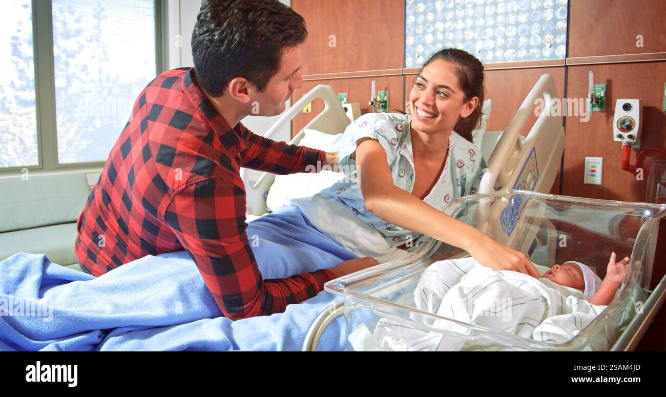 Loving Parents With Newborn Baby Boy Lying In Hospital Bed And Cot ...