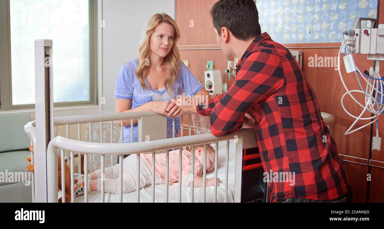 Concerned Parents Visiting Baby Daughter Lying In Hospital Cot Stock Photo - Alamy