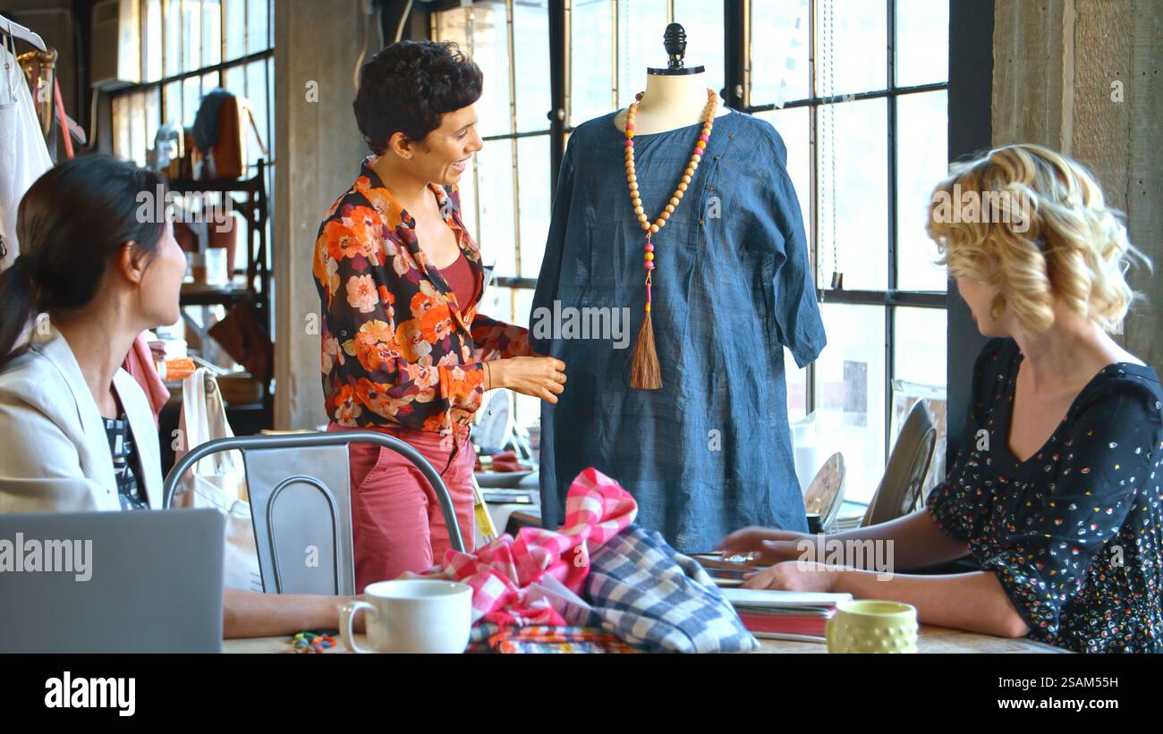 Three Female Fashion Designers In Studio Meeting Discussing Garment On ...