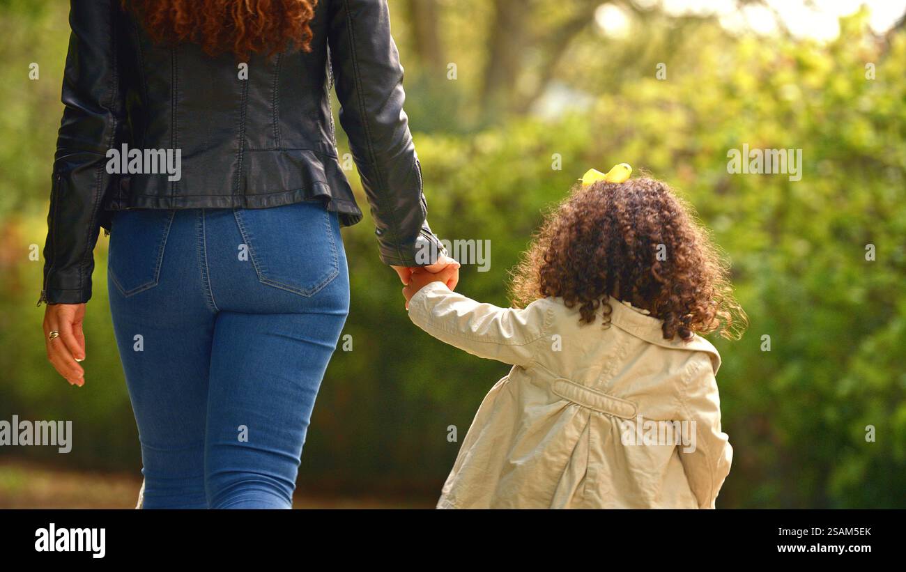Rear View Of Mother Holding Daughter's Hand Walking Through Trees In ...