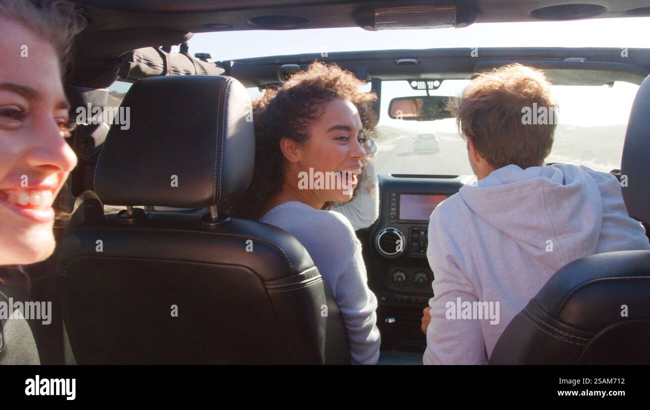 Close Up Of Group Of Young Friends On Road Trip Driving In Convertible ...