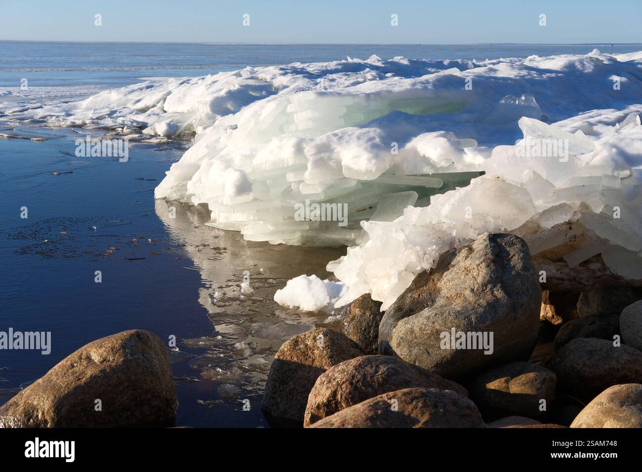 Frozen shoreline with stacked ice and rocks. Nature in winter, blue ...