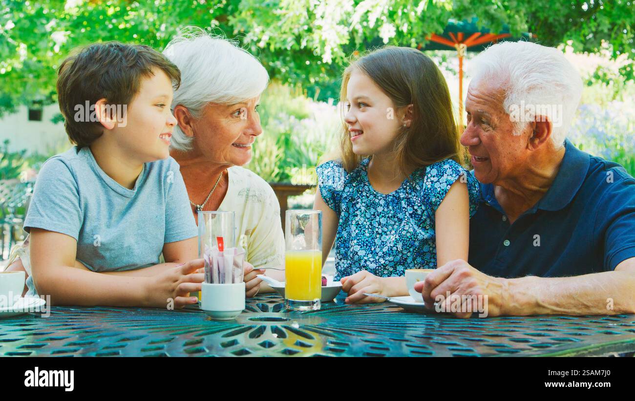 Grandparents With Grandchildren At Table Enjoying Snack At Outdoor Cafe ...