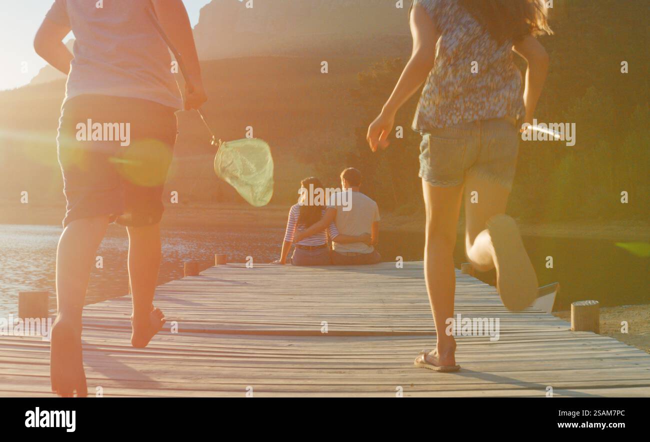 Rear View Of Family Having Fun With Fishing Nets On Wooden Jetty By ...