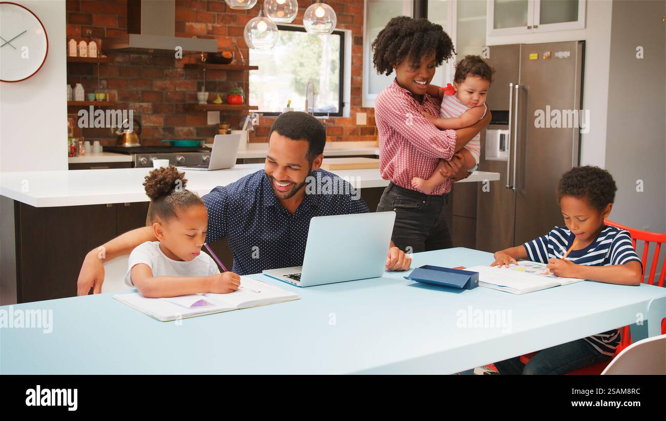 Family At Home With Father Helping Children With Homework Whilst Mother ...