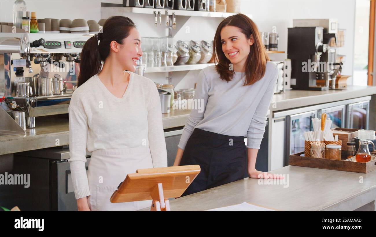 Two Smiling Female Owners Or Workers Behind Counter In Coffee Shop ...