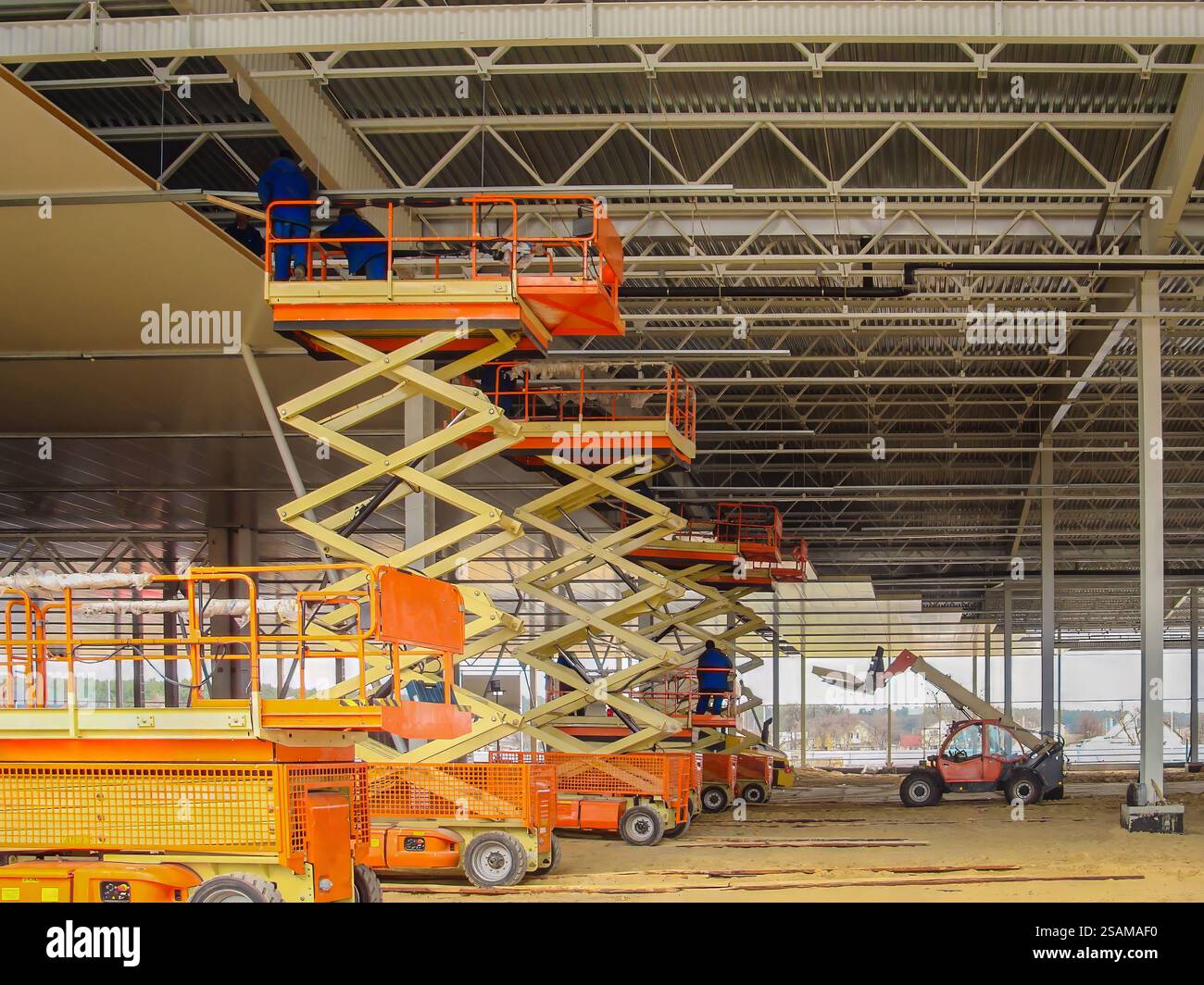 Scissor lifts used for sandwich panel ceiling installation at an ...