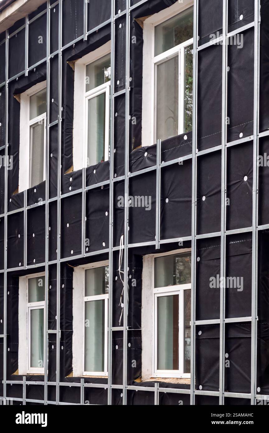 Detailed view of installing facade insulation with metal profiles and wind barrier membrane ...