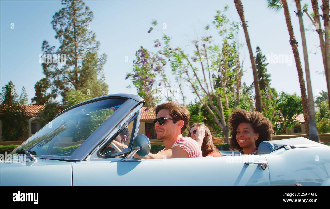 Side View Of Group Of Young Friends On Road Trip Driving In Classic ...
