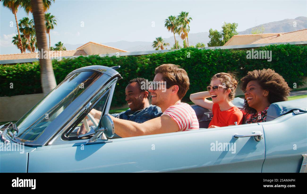 Side View Of Group Of Young Friends On Road Trip Driving In Classic ...