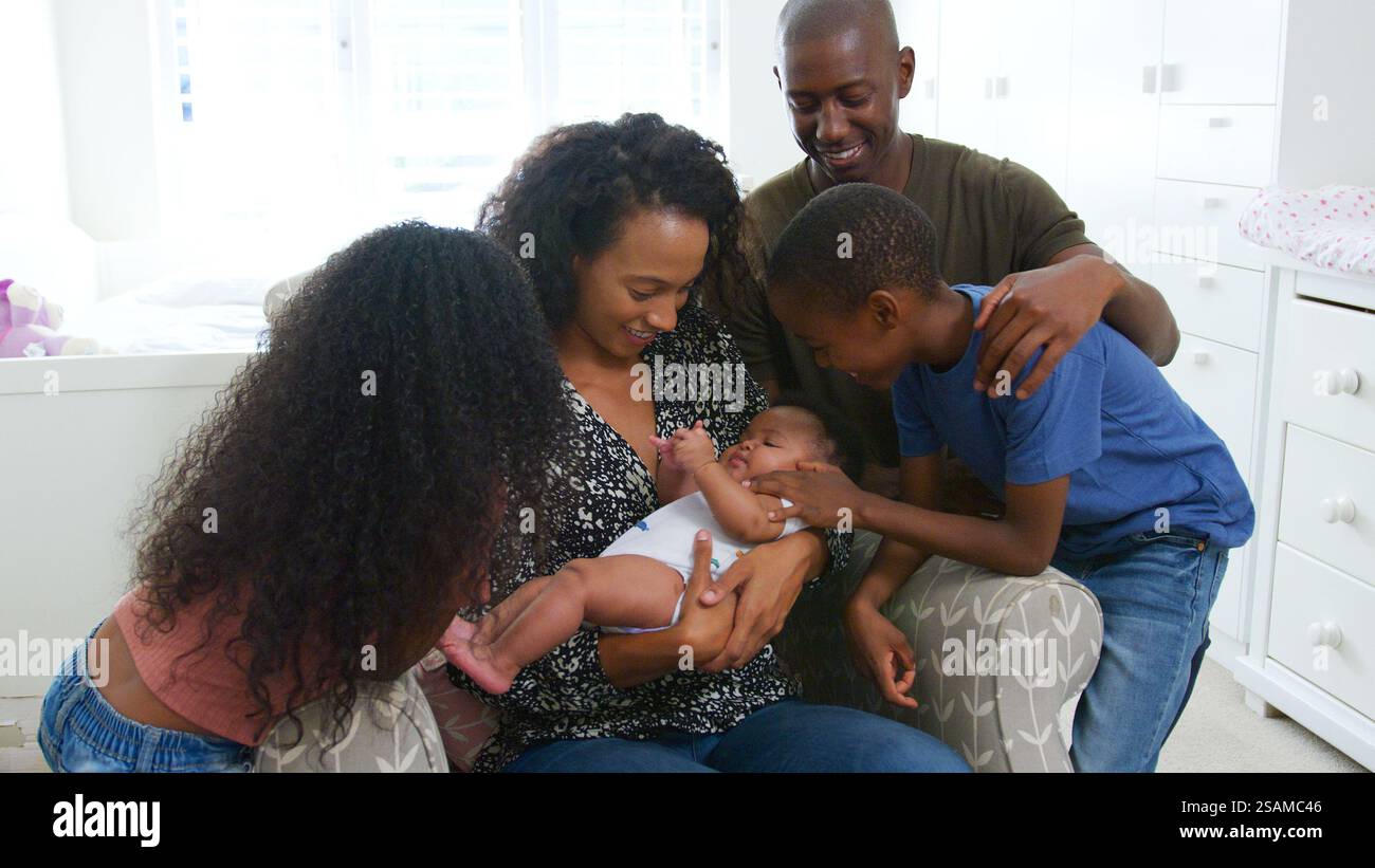 Loving Family In Nursery At Home Cuddling Baby Son Sitting In Chair ...