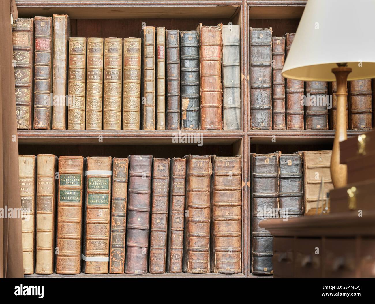 Well worn leather bound-books on shelves at Wren library, Trinity ...