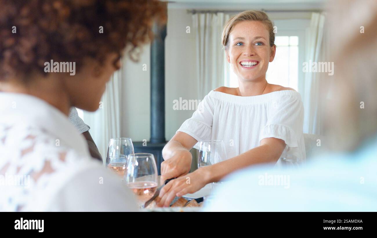Group Of Young Friends Sitting Around Table At Home Enjoying Meal ...