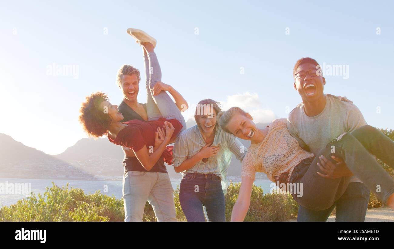Couples Having Fun With Men Lifting Up Women As Group Of Friends Walk ...