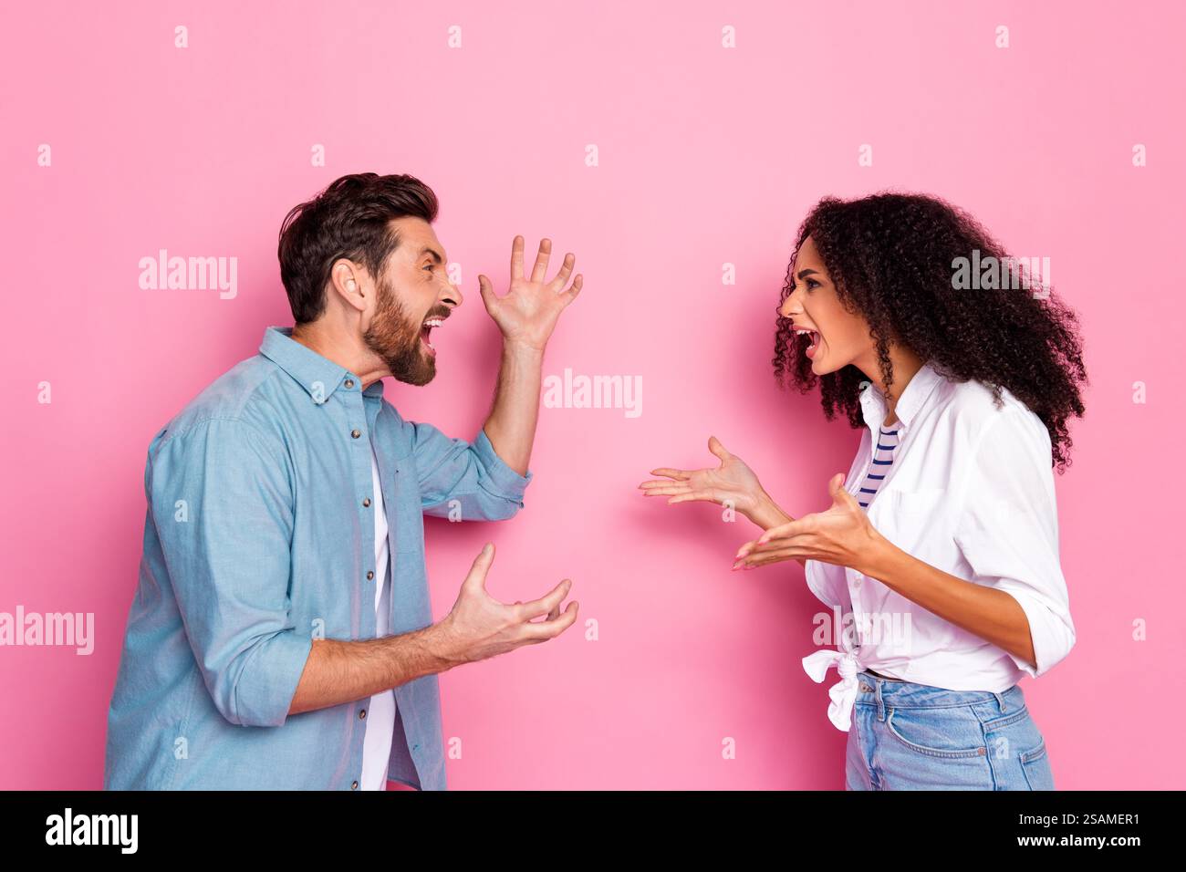 Young couple engaged in animated discussion against pink background ...