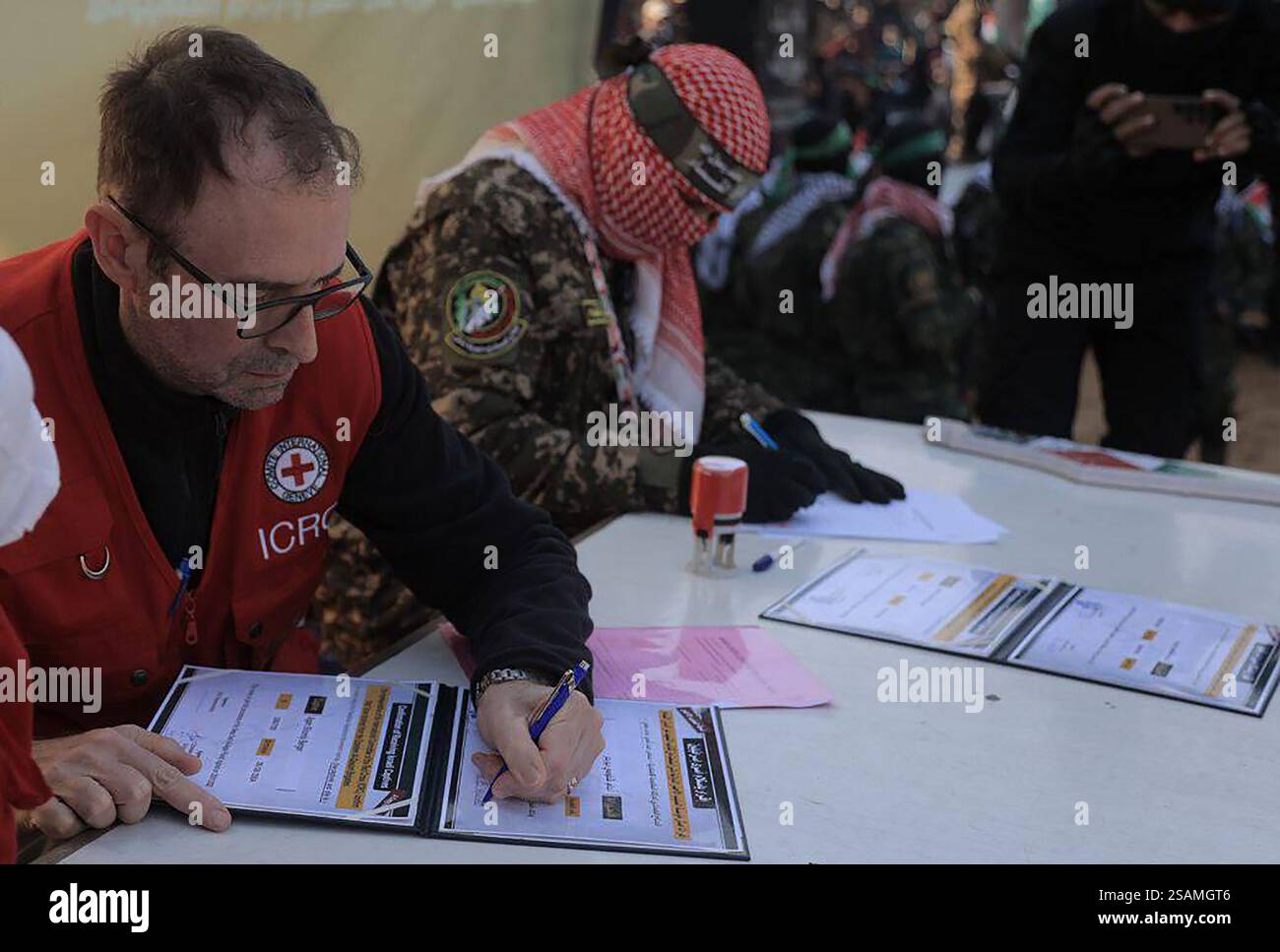 A member of the Red Cross team signs documents before Hamas militants ...