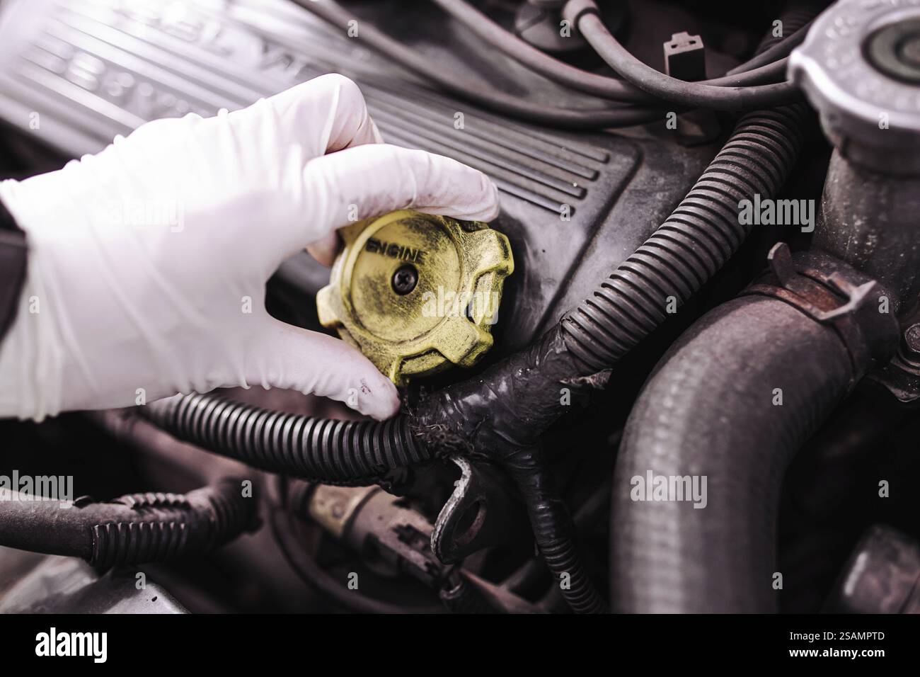 A gloved hand removing the cap from a car engine for maintenance Stock ...