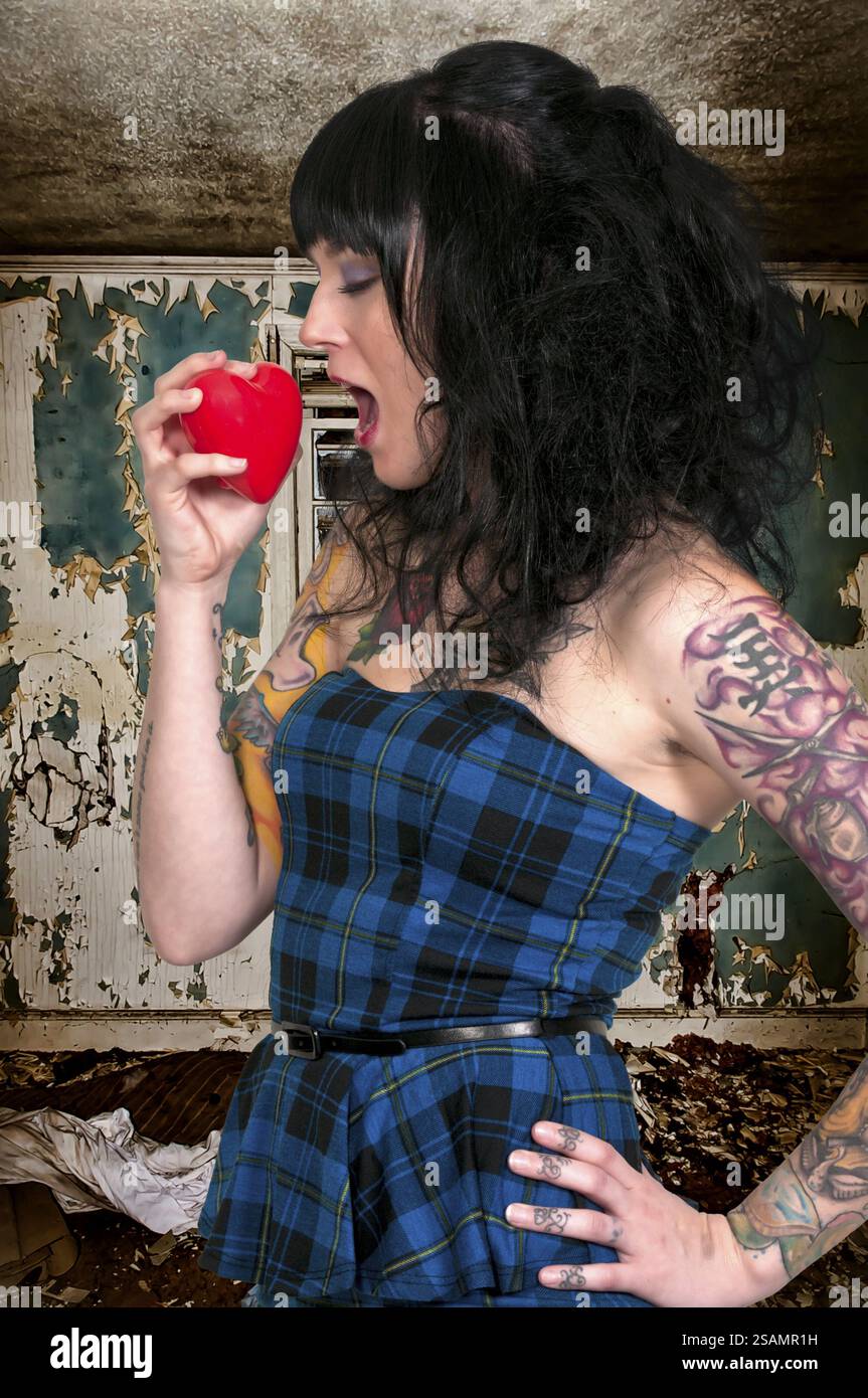 Beautiful woman eating a big red heart Stock Photo - Alamy