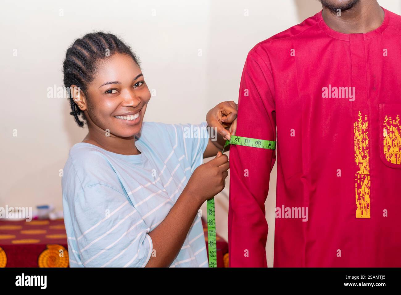 Female Tailor is measuring her client with measuring tape Stock Photo ...