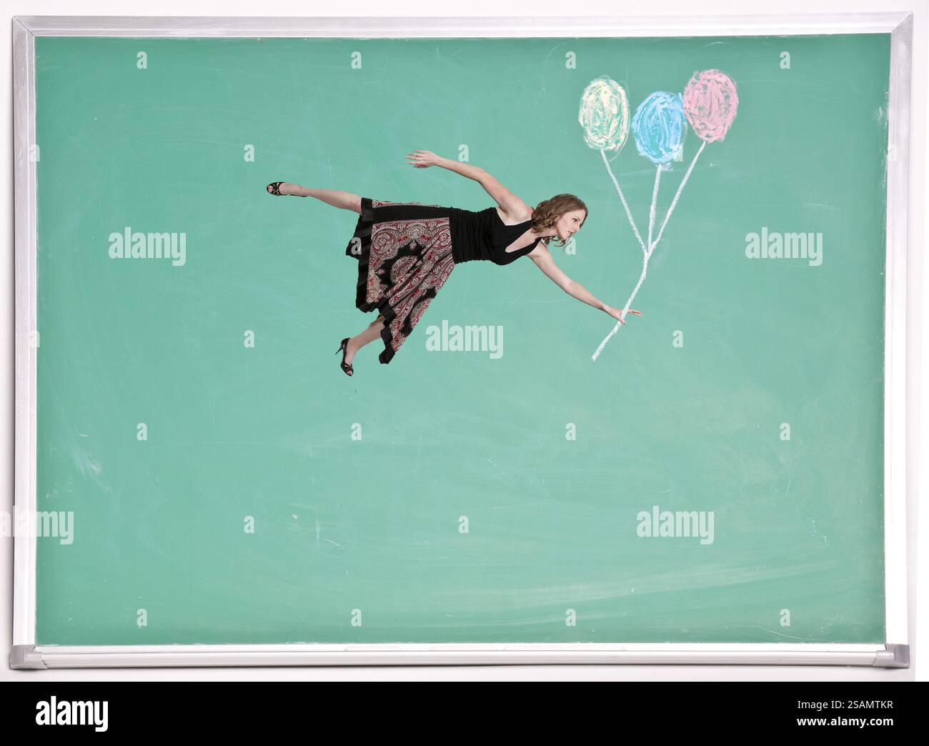A beautiful young woman floating with balloons on a chalkboard Stock ...