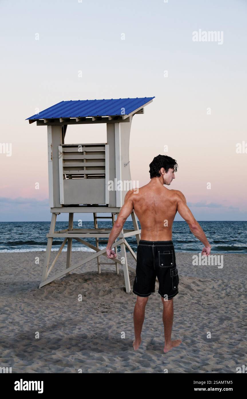Male lifeguard standing on the beach by a lifeguard stand Stock Photo ...