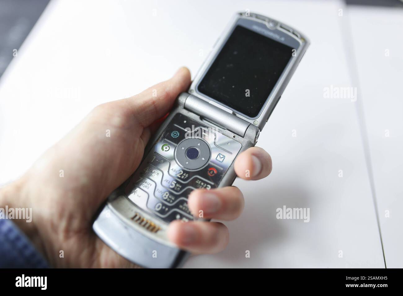Hand holding an open Motorola flip phone, emphasizing screen and keypad ...