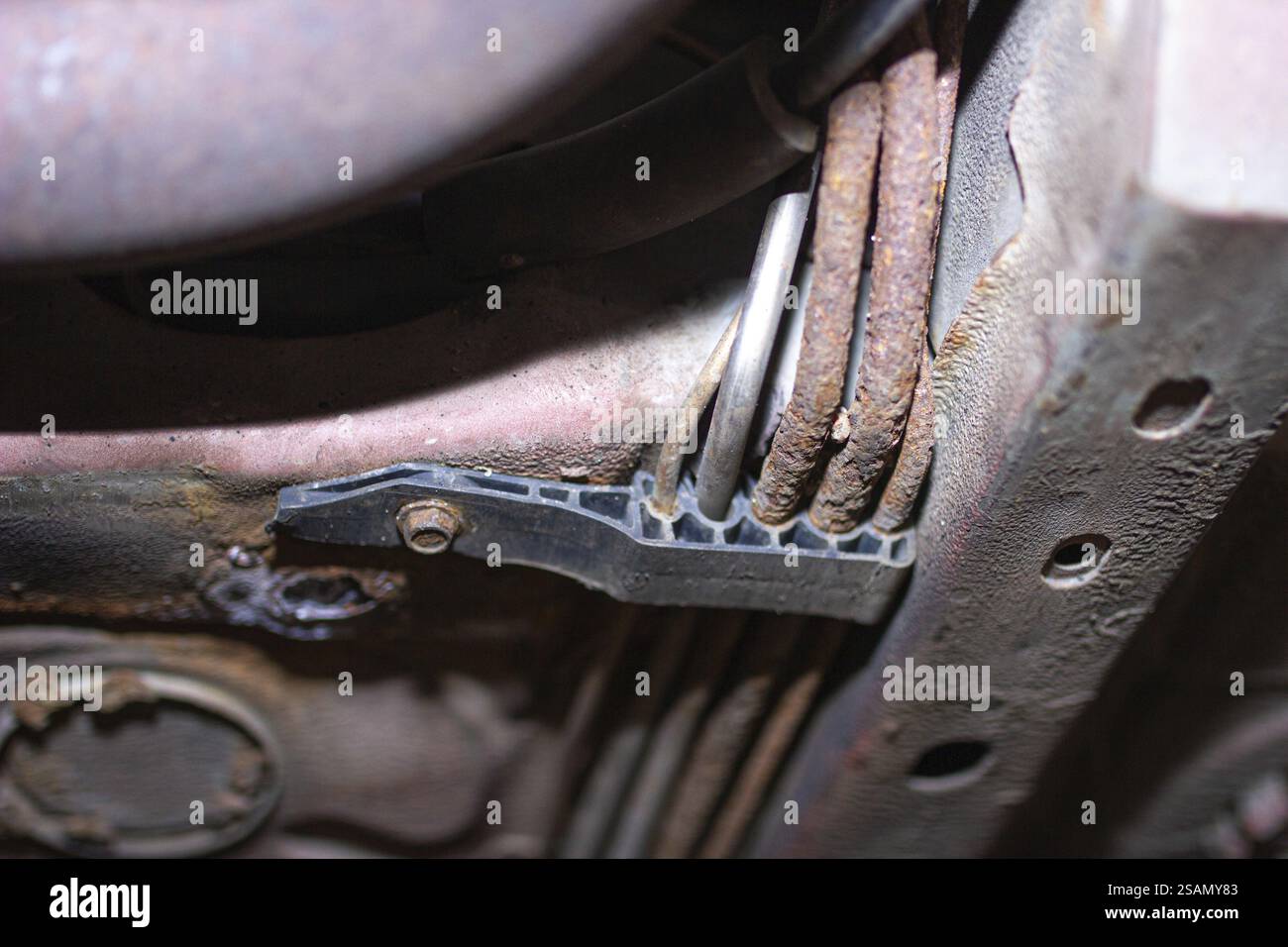 Close-up of corroded pipes on the underside of a car, highlighting rust ...