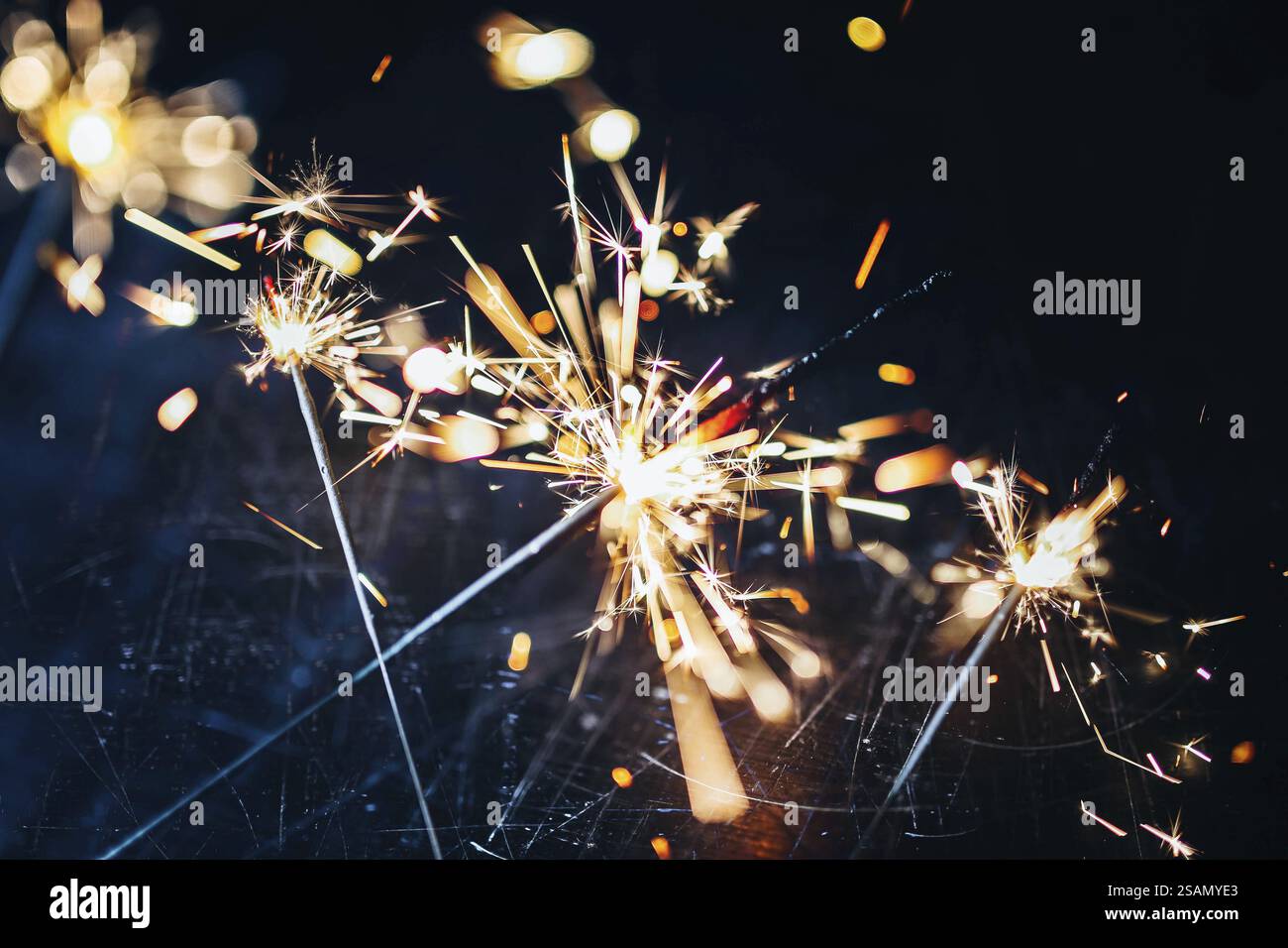 Bright sparklers emitting dynamic sparks and light against a dark ...