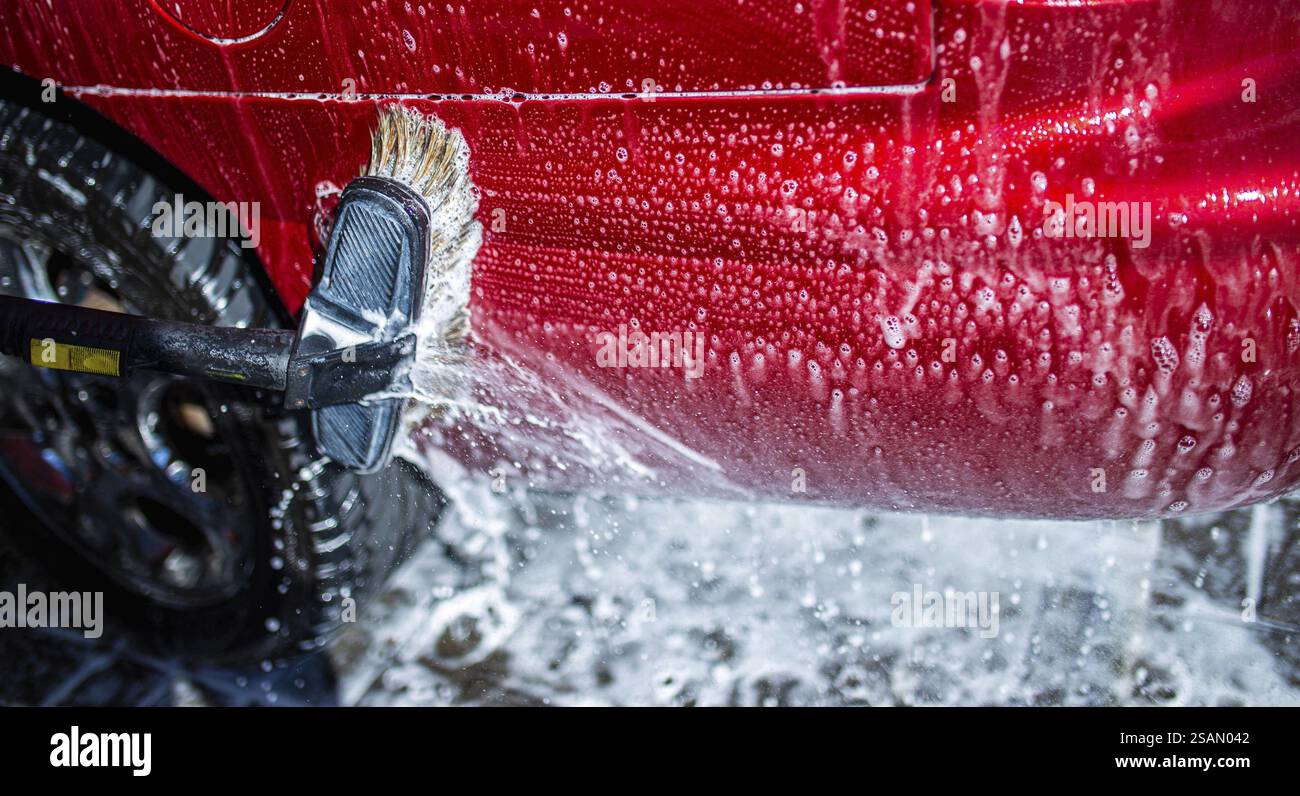 Close-up of a red car being washed with a soapy brush Stock Photo - Alamy