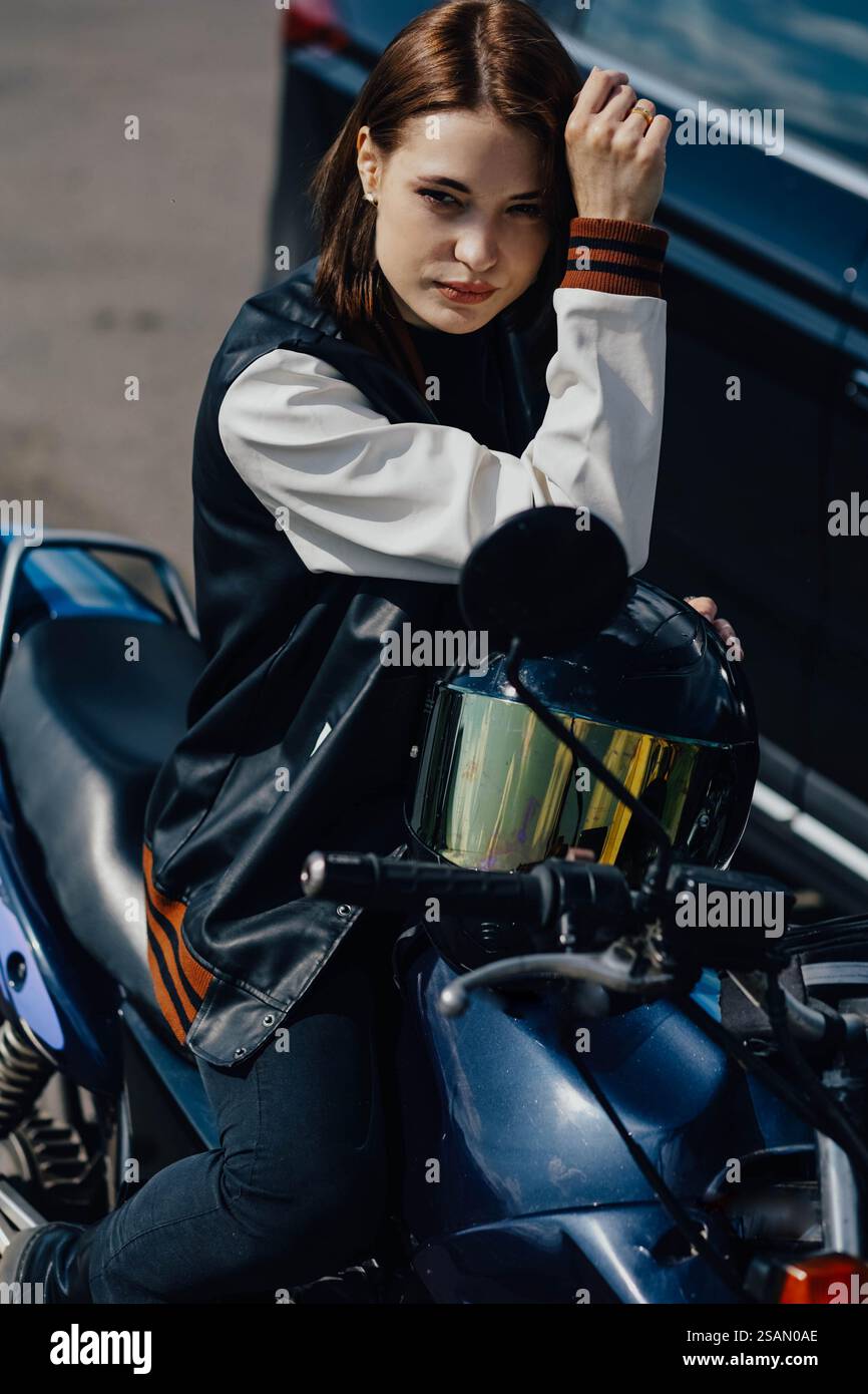 Confident woman poses on a motorcycle, urban background Stock Photo - Alamy