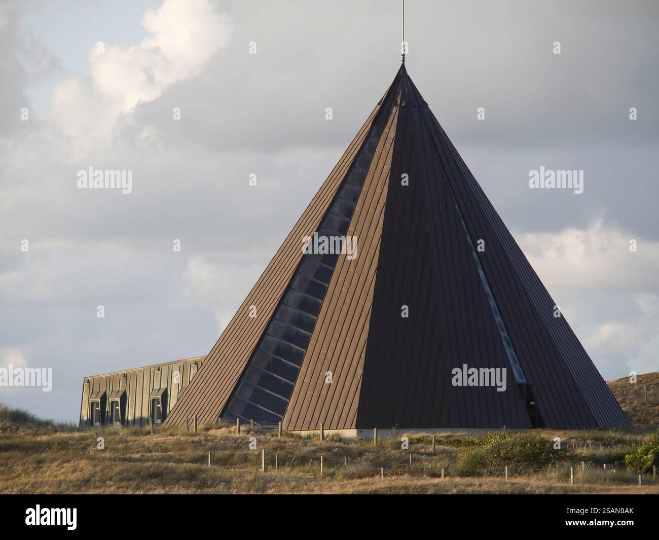 Modern, pyramid-shaped building in front of a slightly cloudy sky ...