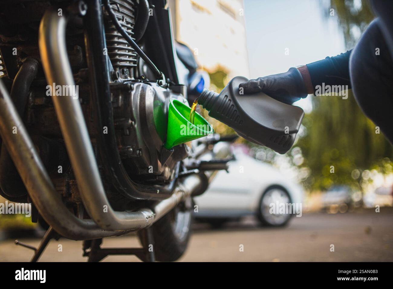 Close-up of a person performing an oil change on a motorcycle engine ...
