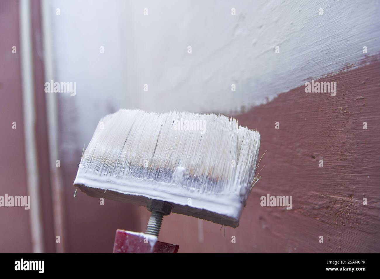 Straight edge of a painted white wall over a red undercoat with a focus ...