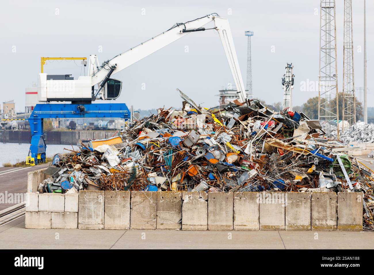 Crane at recycling facility loading large scrap metal pile with wind ...