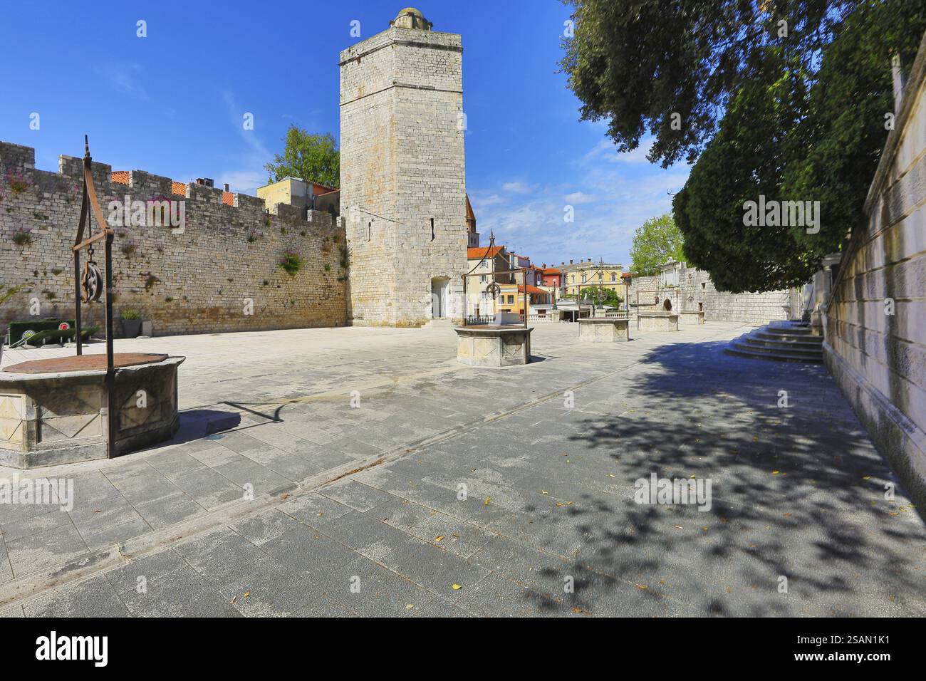 Medieval castle complex with high stone walls and a large tower, sunny ...