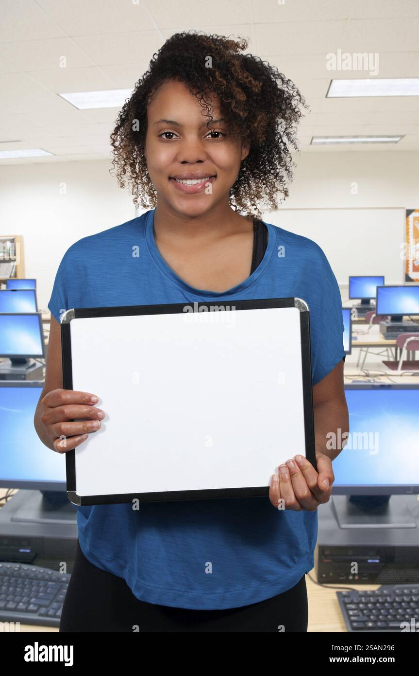 Beautiful young woman teacher holding up a blank sign Stock Photo - Alamy