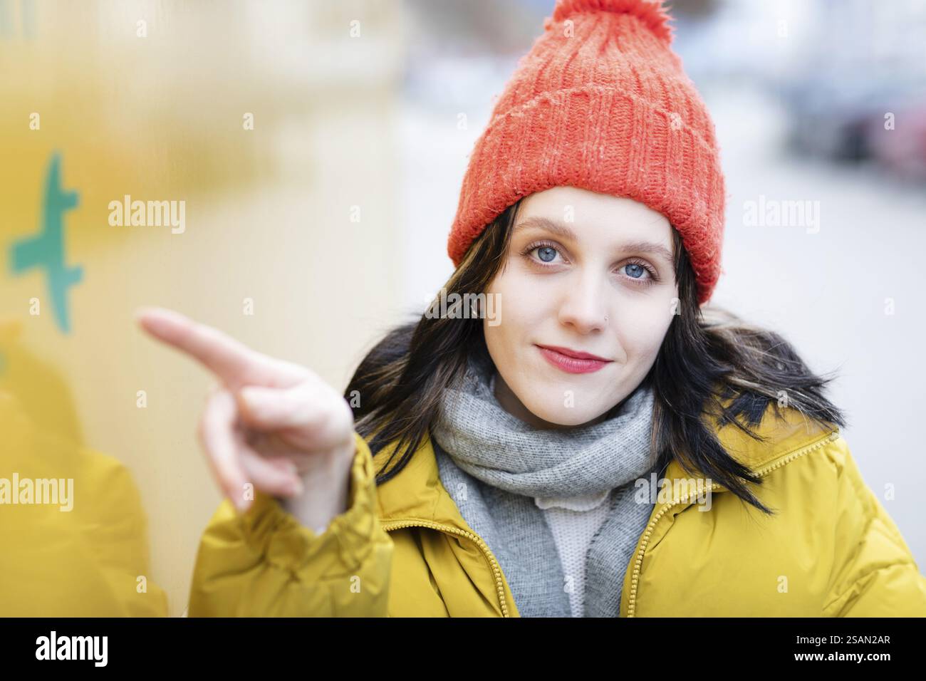 Woman with red hat and yellow jacket points with finger at large ...