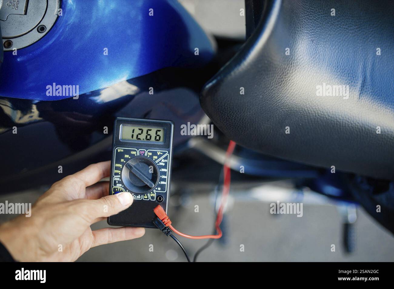 Person using a multimeter to measure voltage on a motorcycle Stock ...